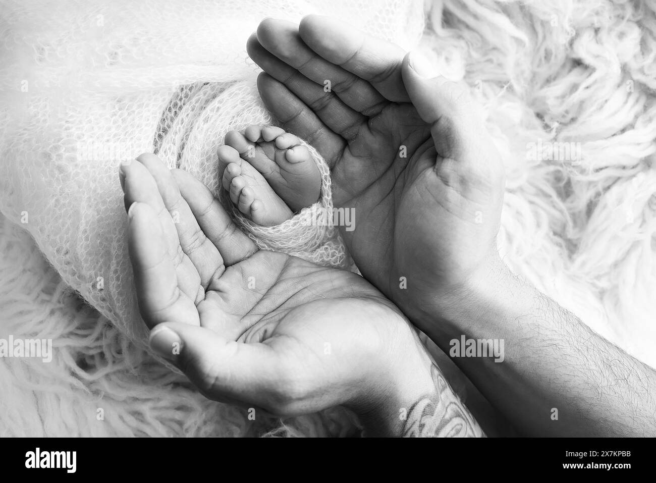 The palms of the father, the mother are holding the foot of the newborn ...