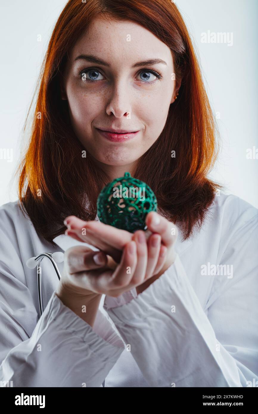 Red Haired Woman In A White Lab Coat Holding A Green Ornamental Ball Symbolizes The Importance
