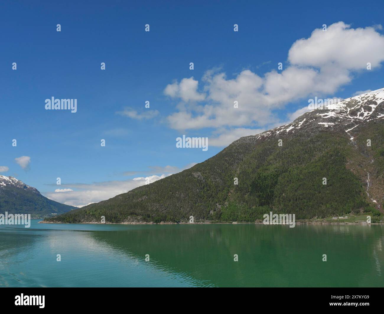 Clear water, snow-capped mountains and blue sky in a peaceful landscape ...