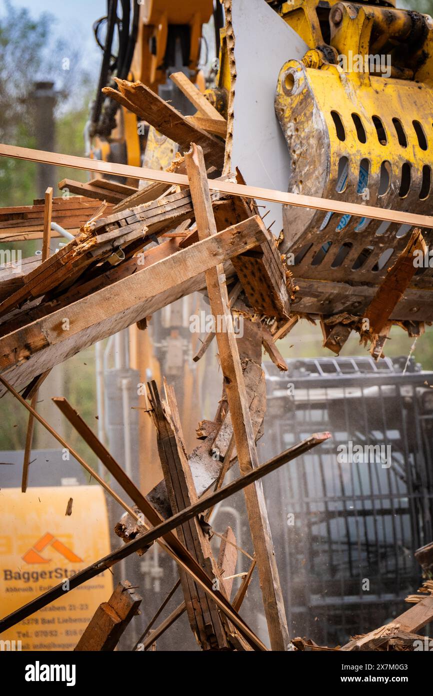 Machine arm of an excavator with hydraulic grab lifting pieces of wood ...