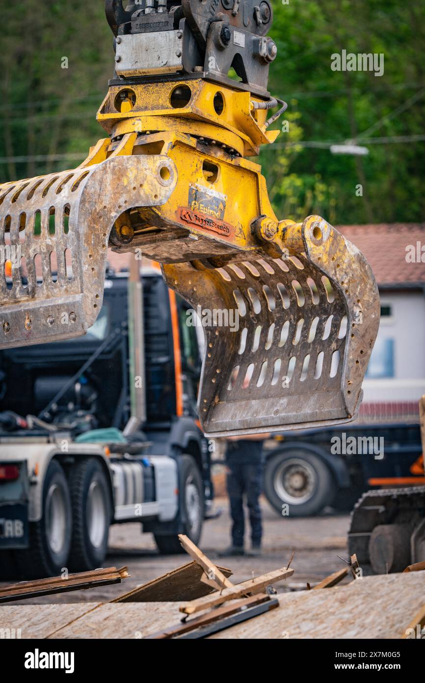 Yellow excavator arm with grapple on a construction site, wood chips ...