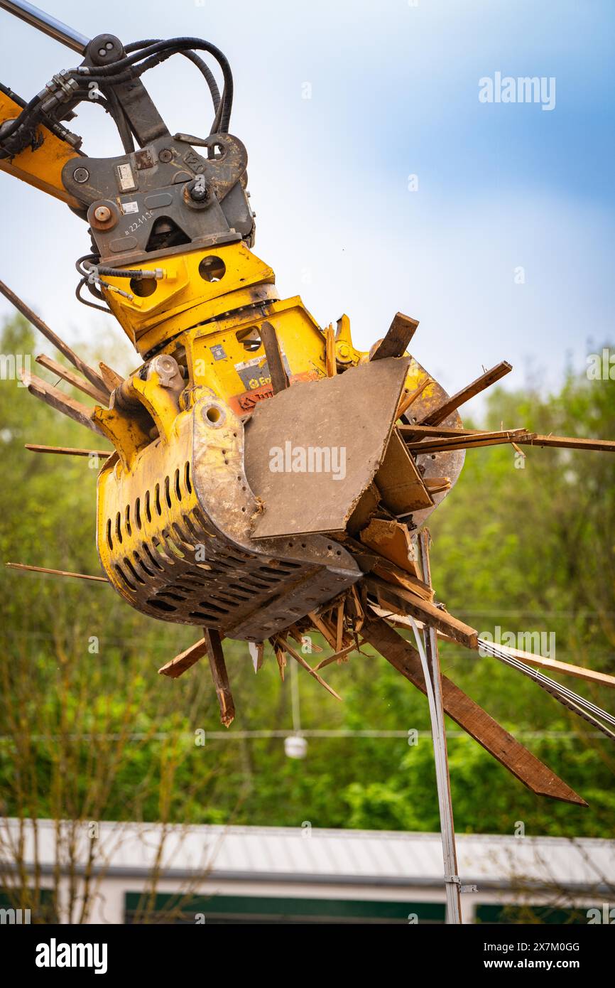 Large yellow hydraulic grab on an excavator lifting pieces of wood ...