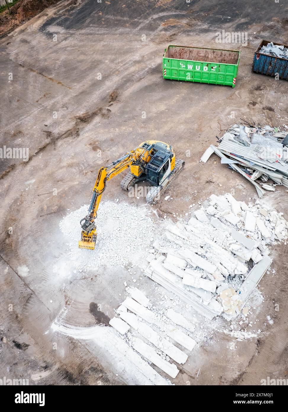 Aerial view of a construction site with a yellow excavator, demolished ...