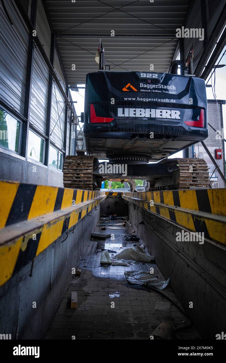 An excavator stands on a lifting platform inside a building, demolition ...