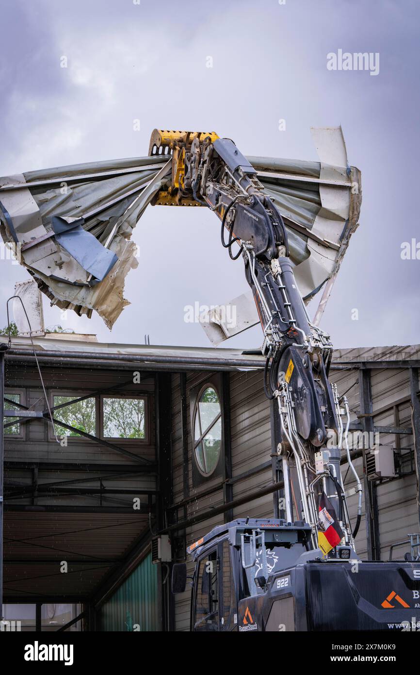 An excavator tears off the roof of a building, debris falls down ...