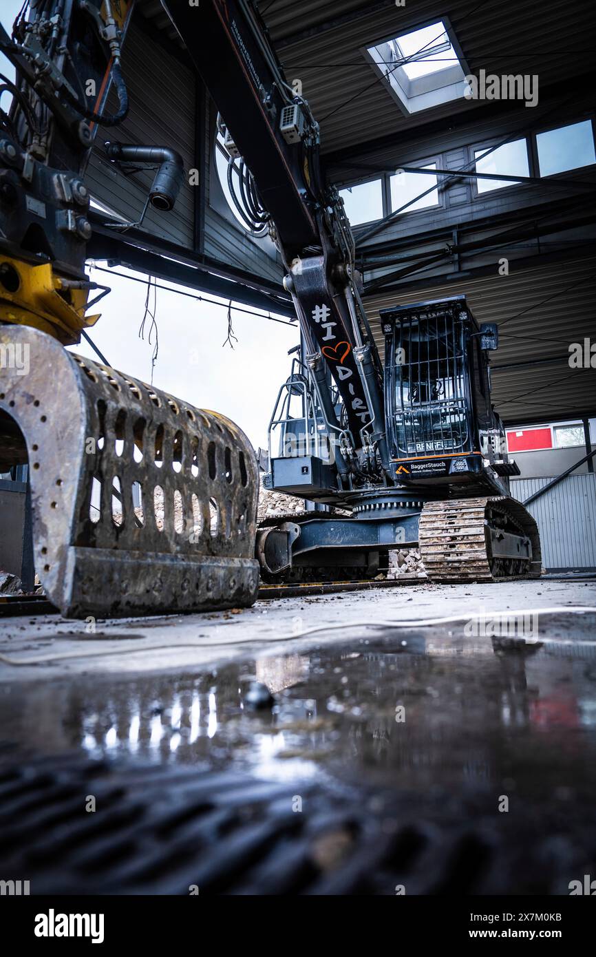 An excavator indoors on a wet floor carrying out demolition work ...