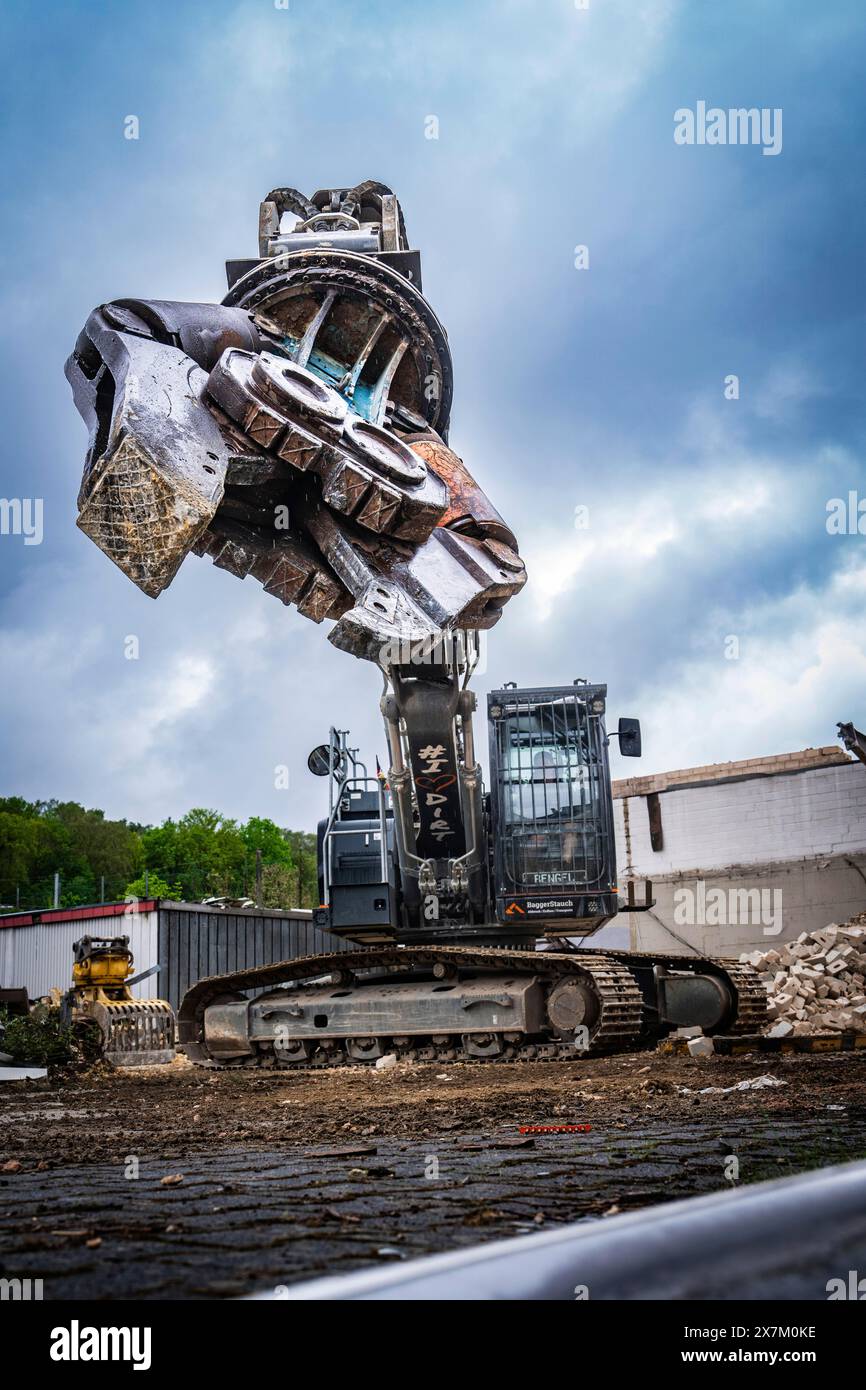 Large excavator with gigantic demolition tongs in the air on a ...