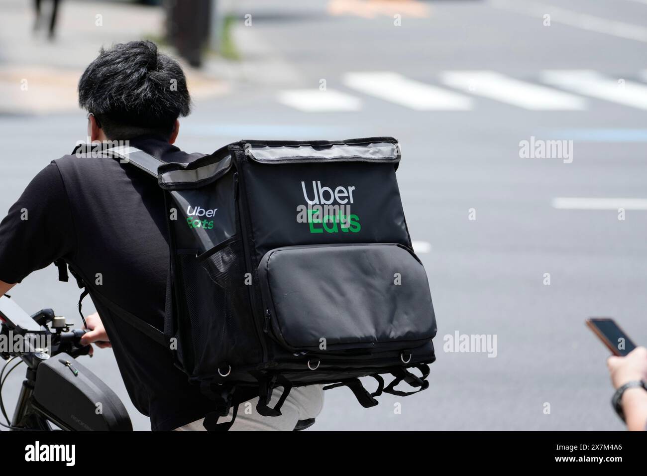 An Uber Eats delivery person rides a bicycle at a business area of ...