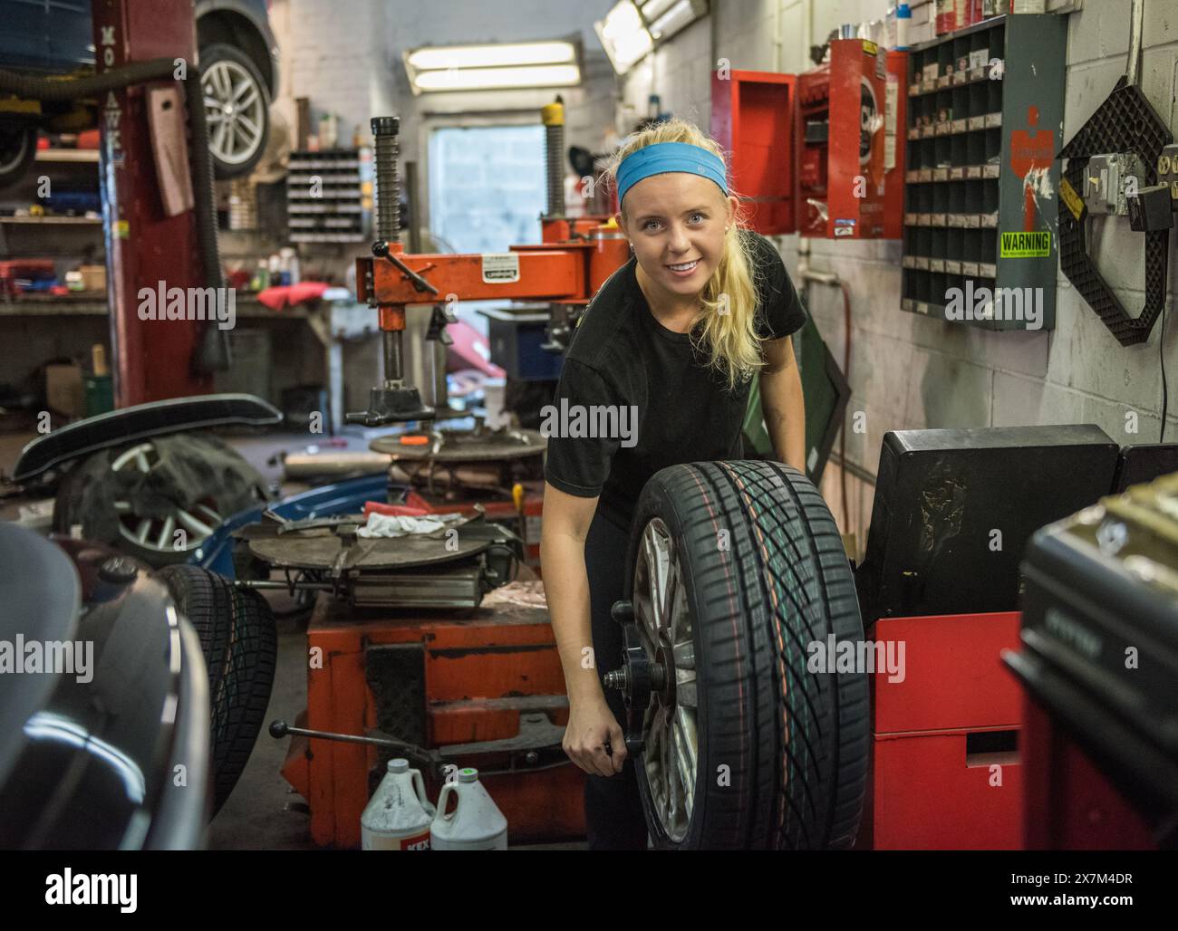 Girl changing a car tire in a garage Stock Photo - Alamy