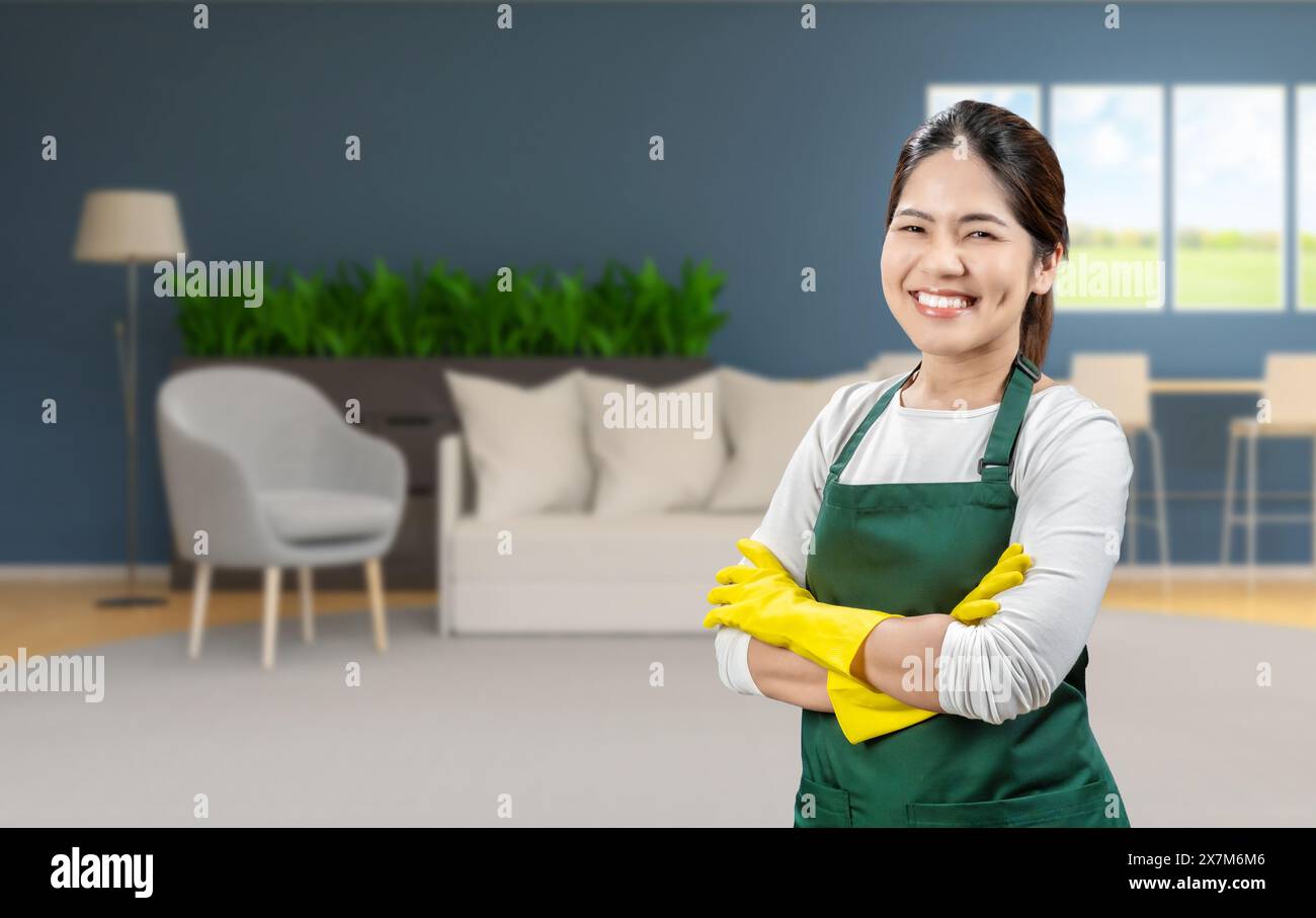 Asian housekeeper wear yellow rubber gloves and green apron smiling in ...