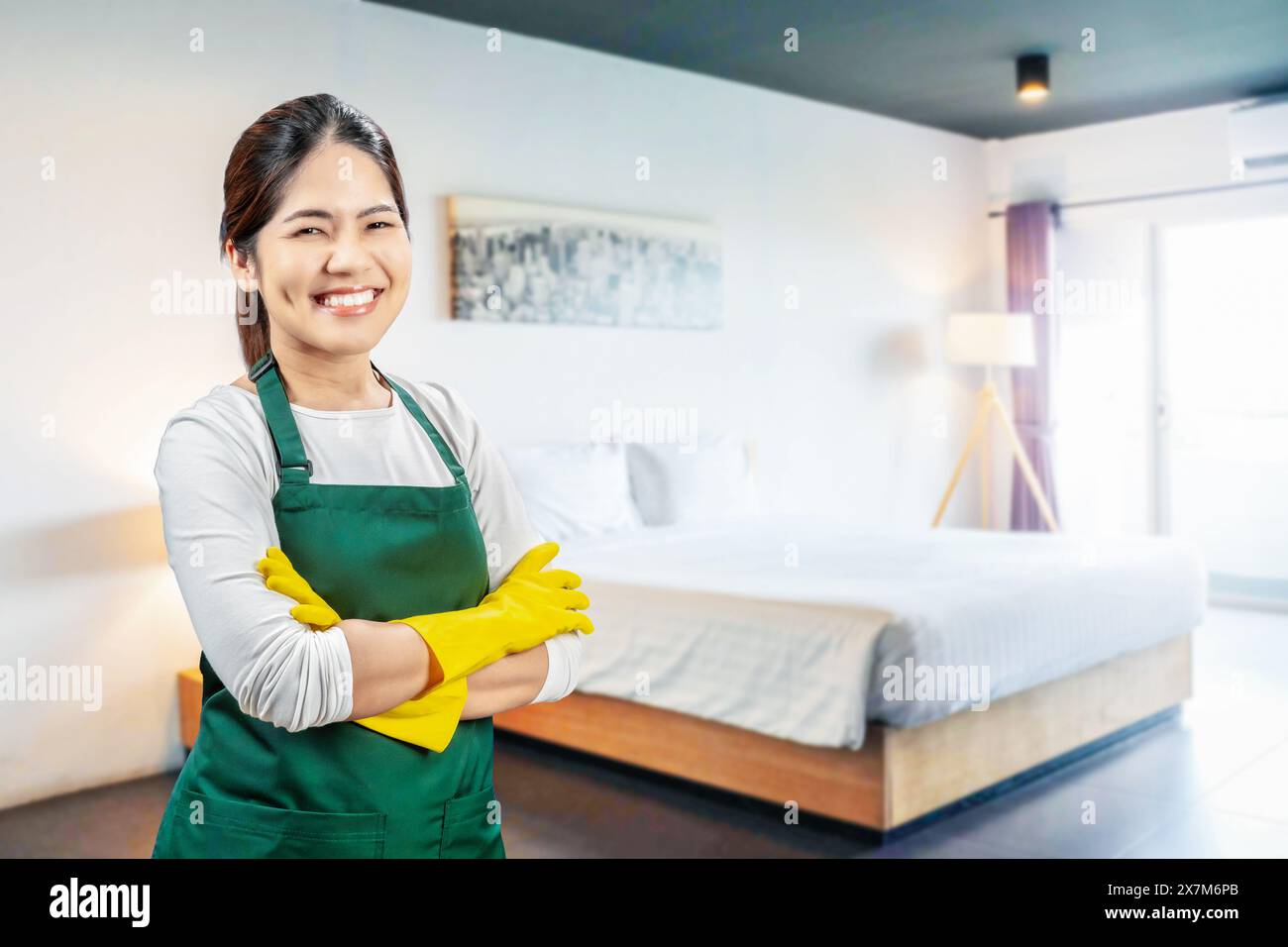 Asian housekeeper wear yellow rubber gloves and green apron smiling in ...