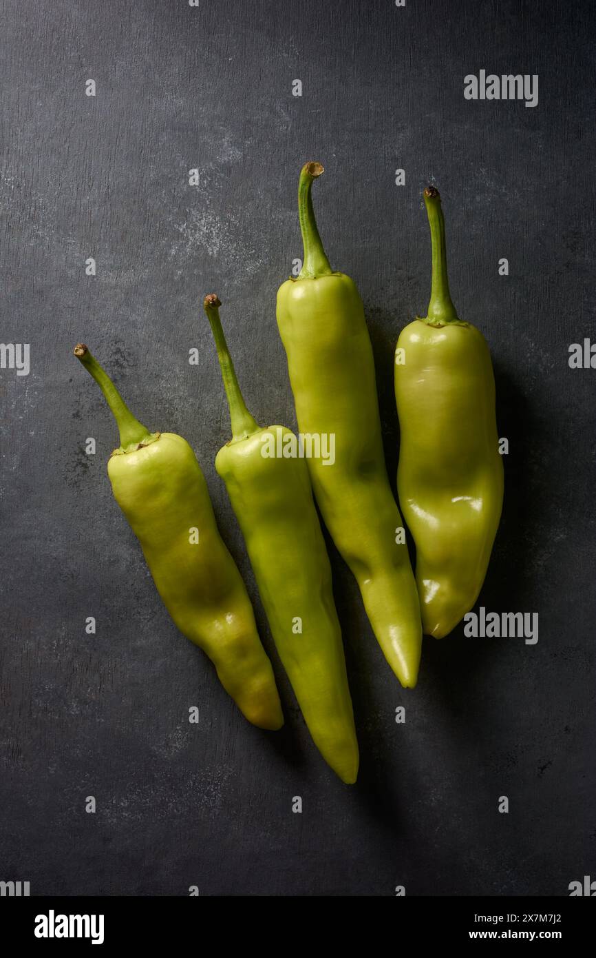 banana peppers on black textured background, long curved shape with ...