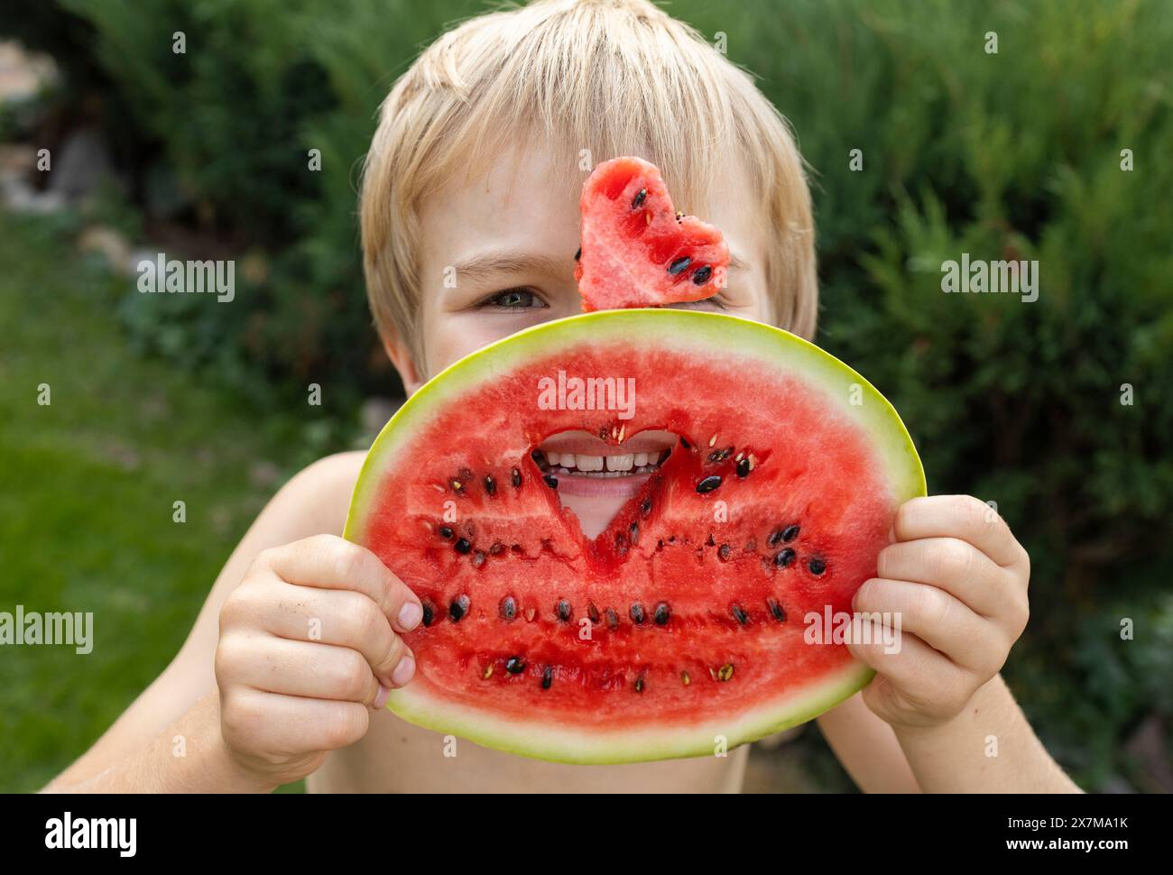 boy's face is hidden behind a piece of watermelon and a heart carved ...