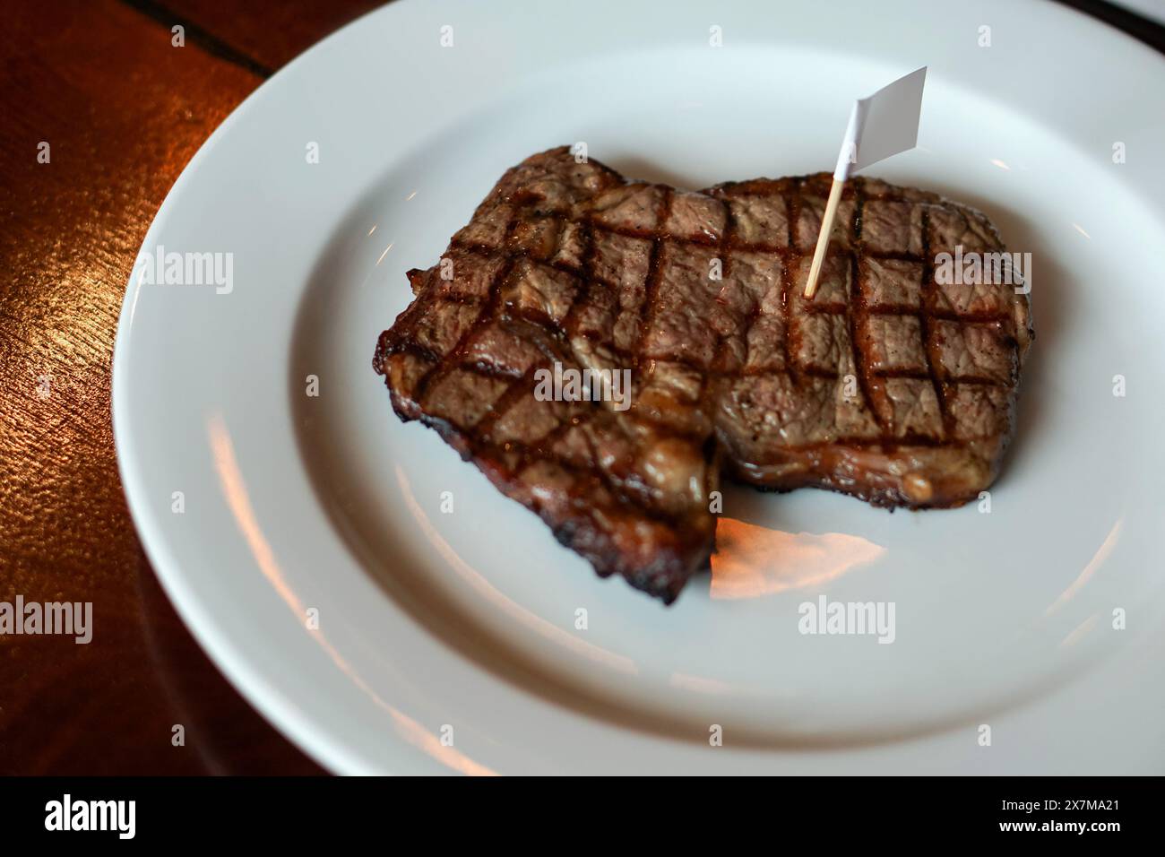 Grilled striploin steak served on white plate. Embroidered the white ...
