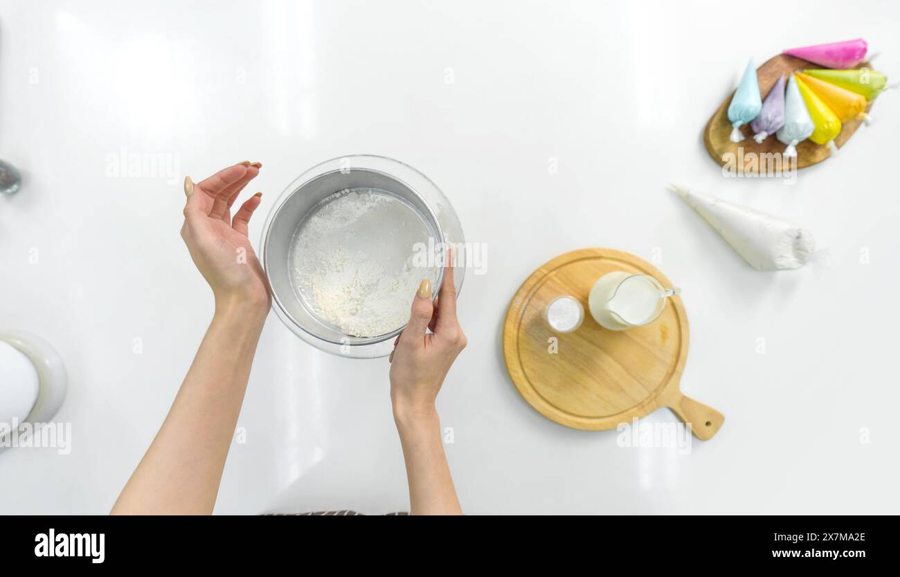 Hand sifting flour in a kitchen with baking ingredient and colorful ...