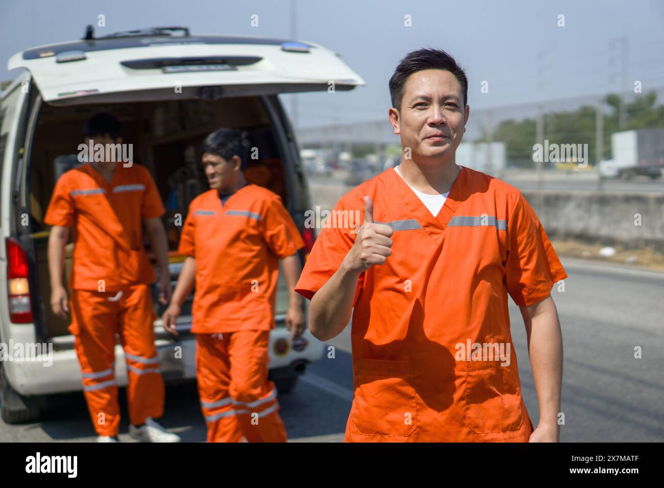 Asian rescue staff in orange uniform stand in front of an ambulance ...