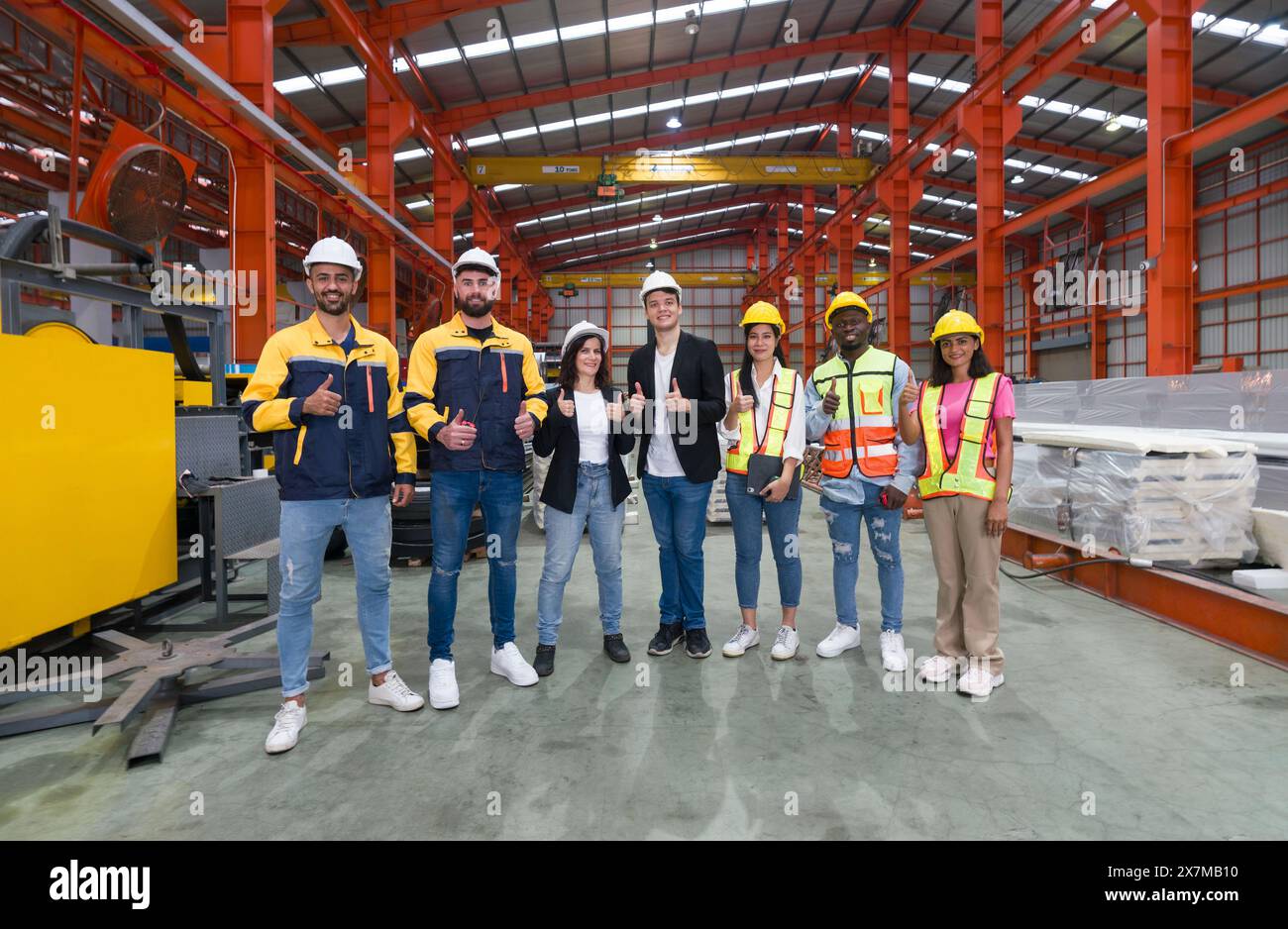 A team of worker stand together for a group photo inside a factory with ...