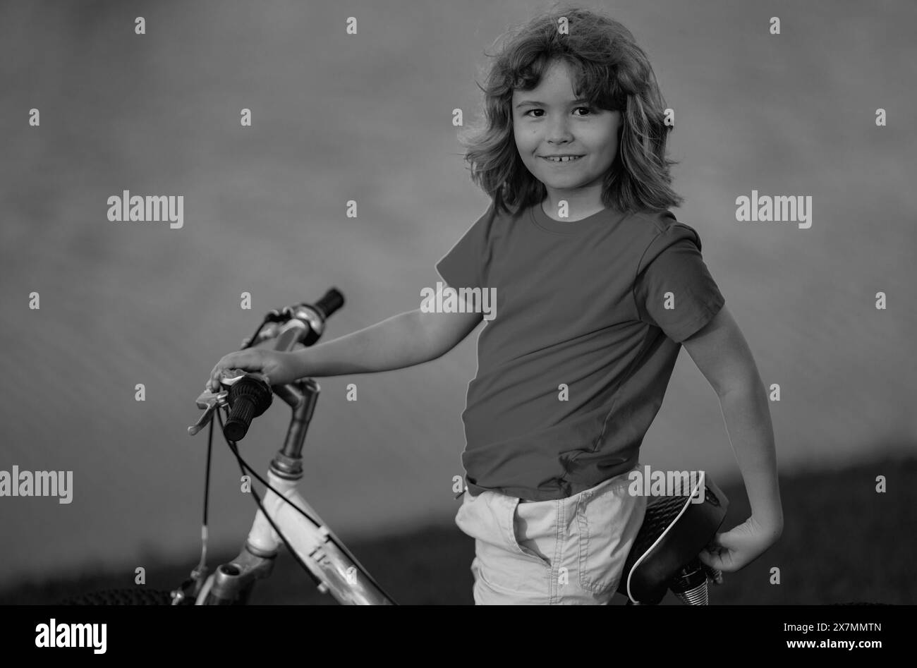 Little kid boy ride a bicycle in the park. Kid cycling on bicycle. Happy smiling child riding a ...