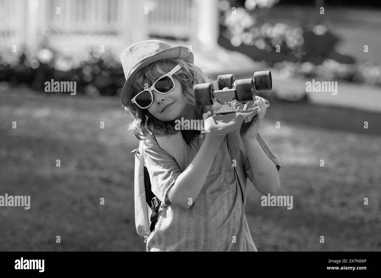 Child with skateboard on summer backyard. Funny kid boy, stylish skater ...