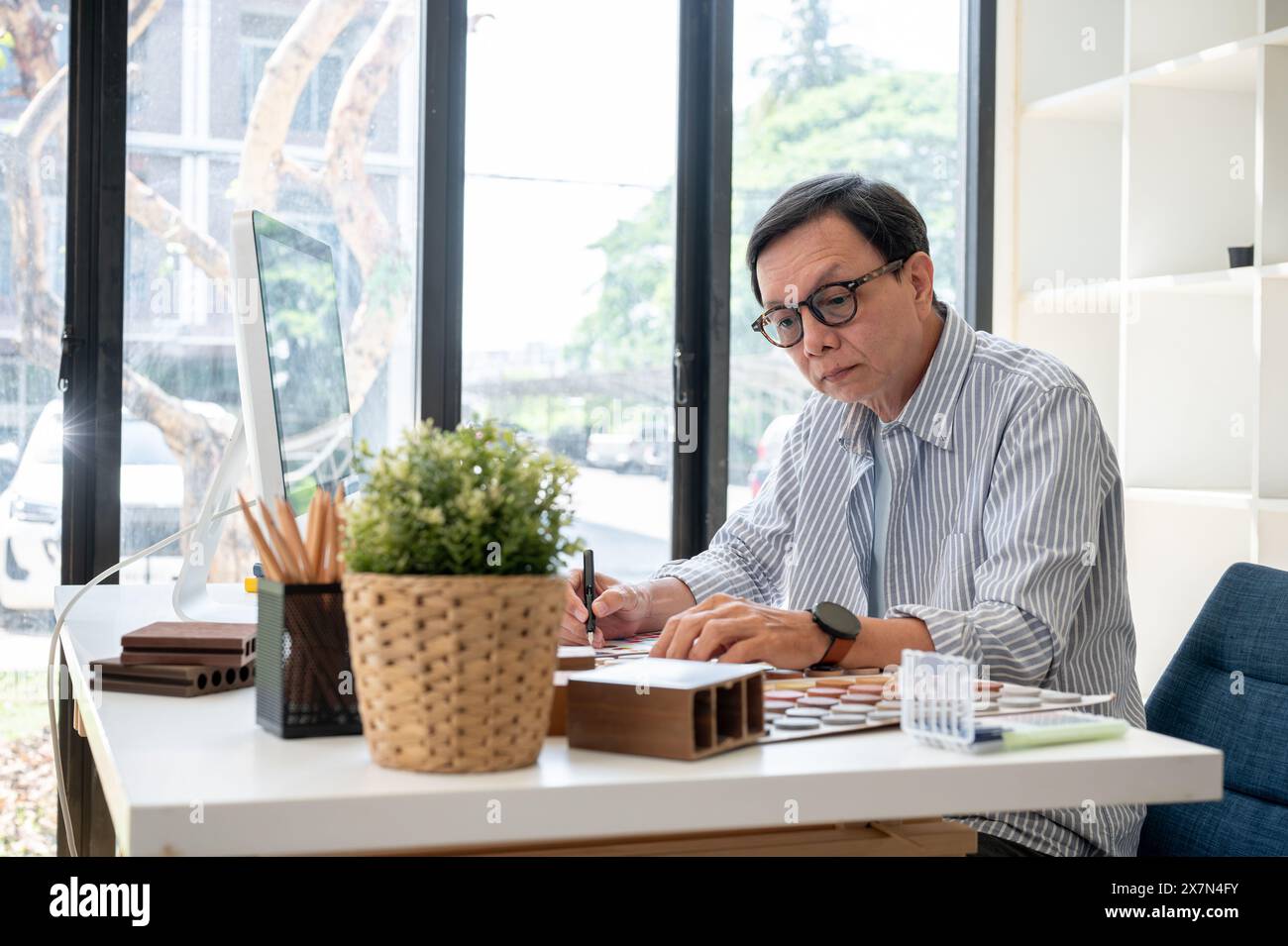 An experienced senior Asian male interior designer or architect is ...