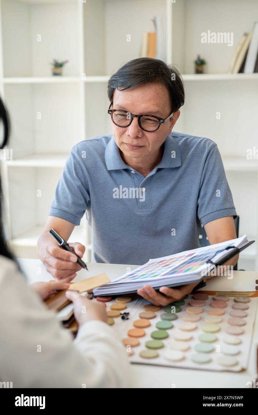 An expert senior Asian male interior designer or architect is having a ...