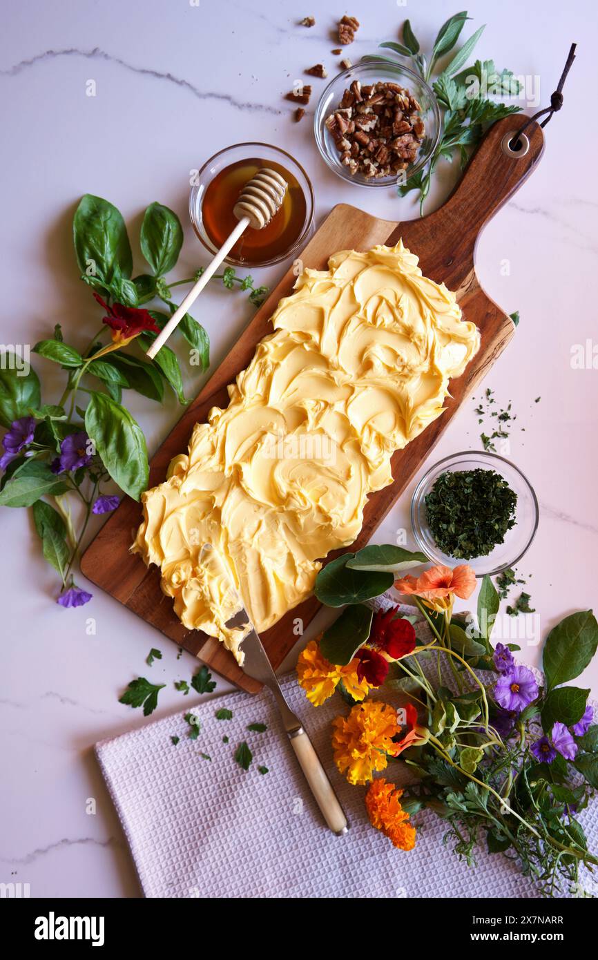 Preparation of herb, pecan and edible flowers butter board Stock Photo ...