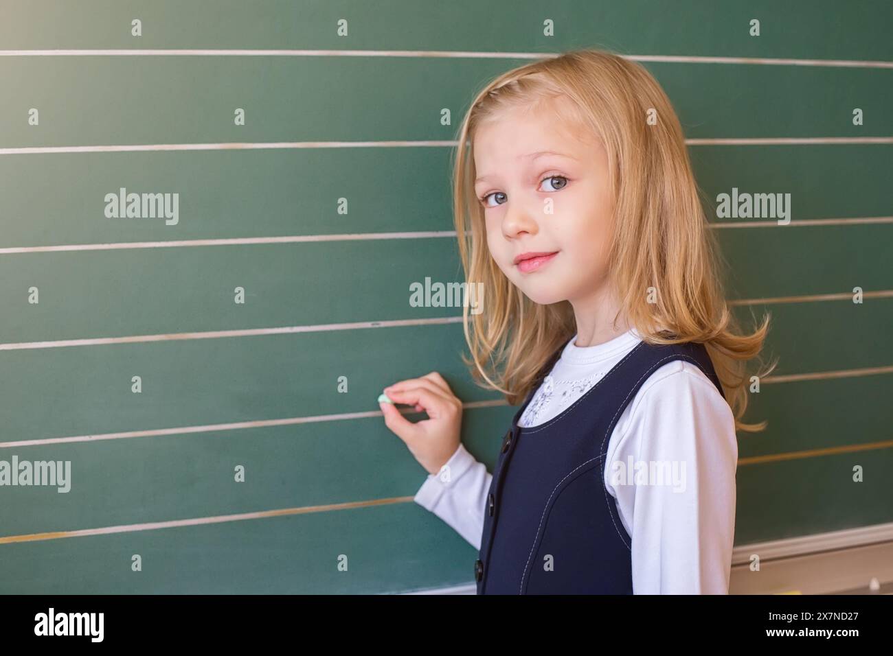 a small beauty of a first grade student at a school near the board ...