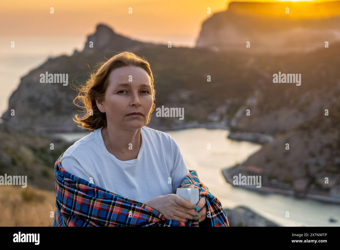 A woman is sitting on a hill with a blanket wrapped around her Stock ...