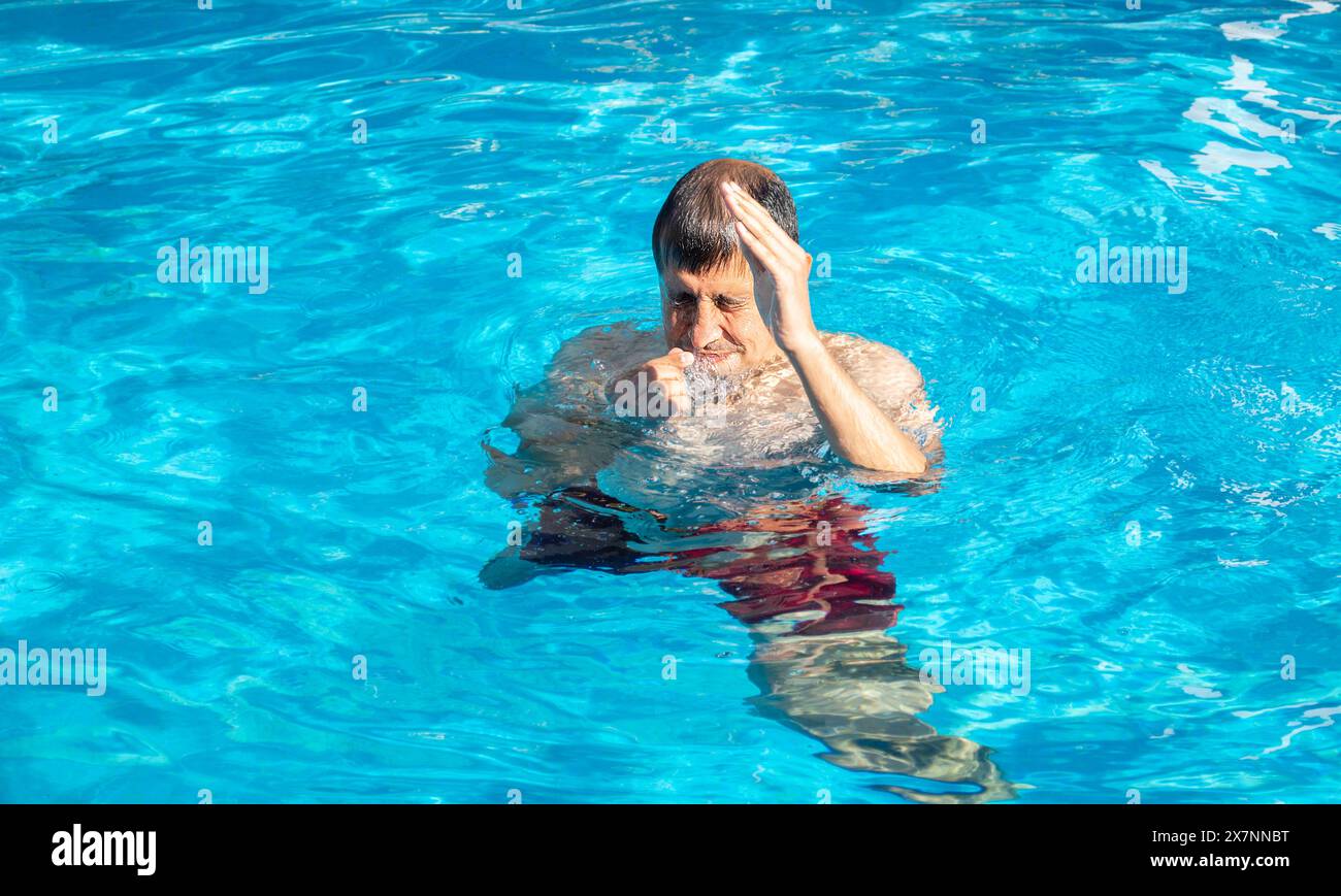 A man with a sore head from the sun floating in the water of a pool or ...
