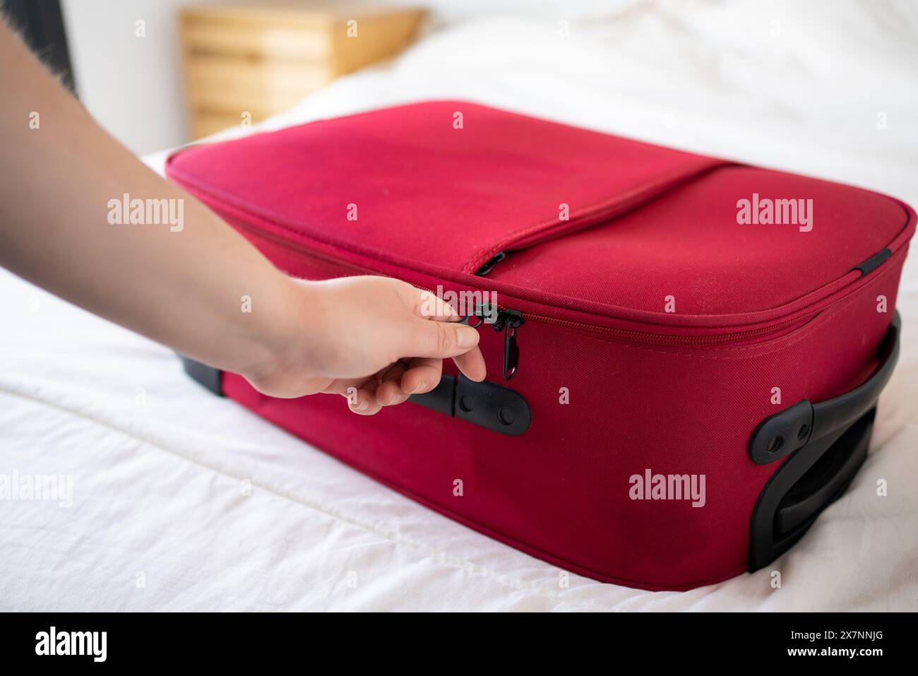 Close up hand of a young woman closing her red suitcase Stock Photo - Alamy