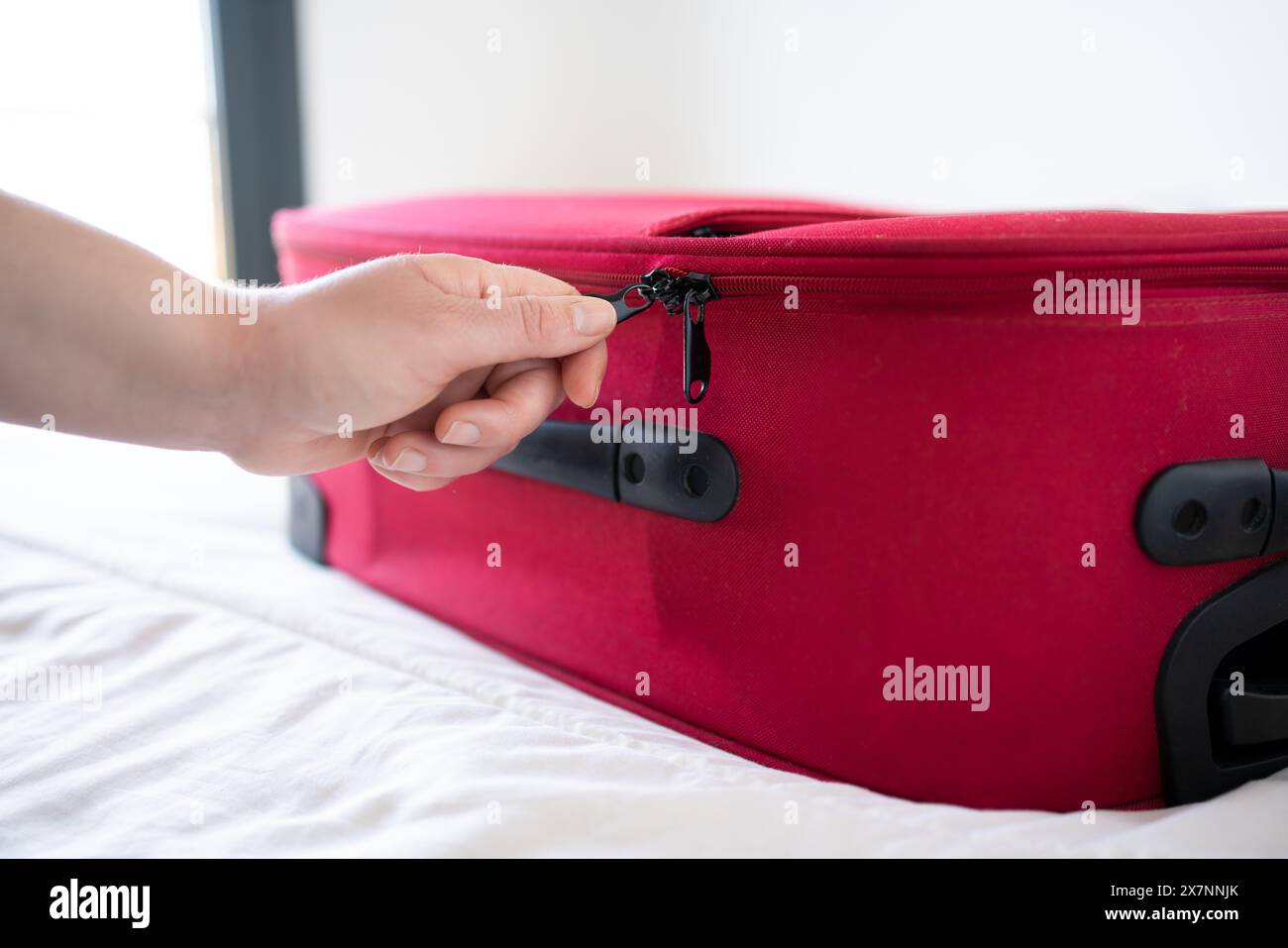 Hand of a young man closing his red suitcase Stock Photo - Alamy