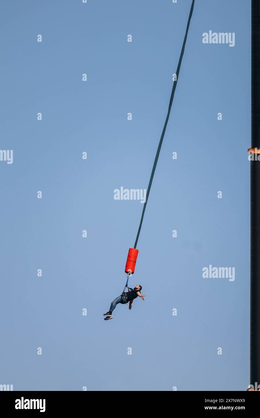Bungee jumping from a great height while connected to a large elastic ...