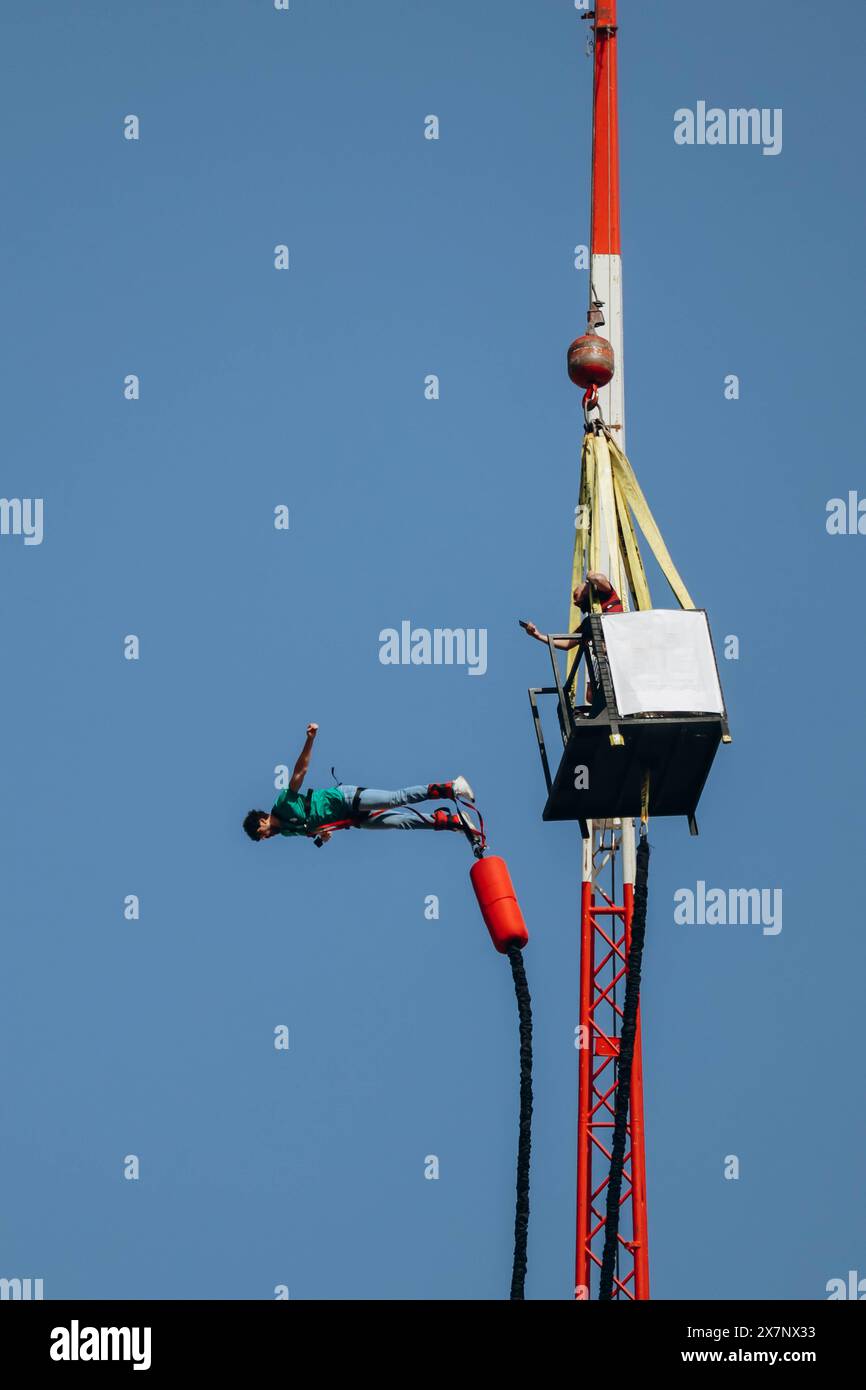 Bungee jumping from a great height while connected to a large elastic ...