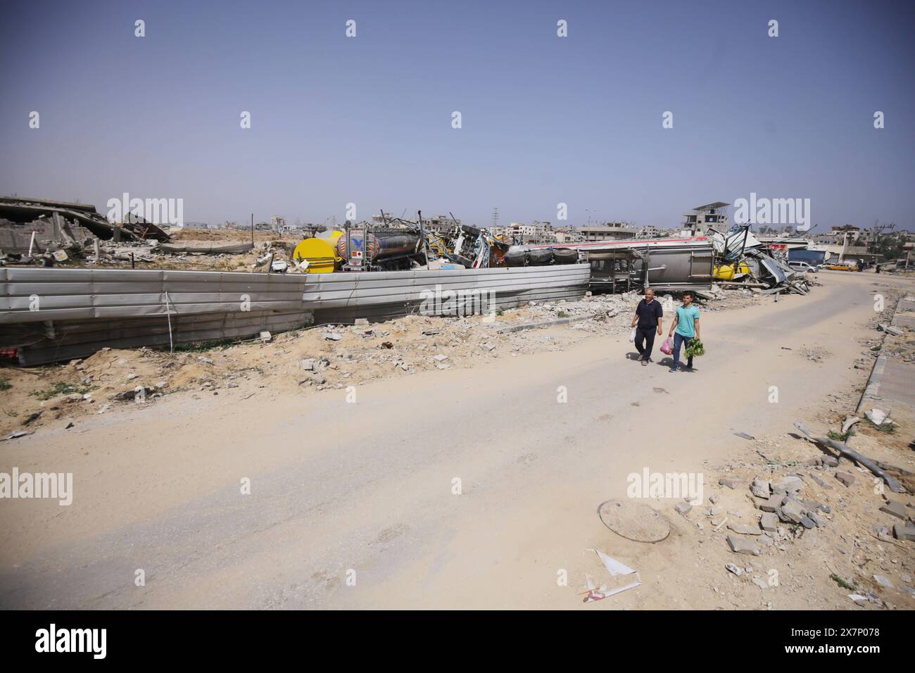 Displaced Palestinians walk between buildings destroyed in Israeli ...
