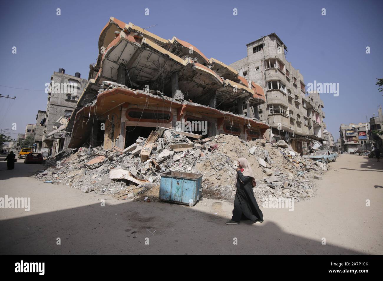 Displaced Palestinians walk between buildings destroyed in Israeli ...