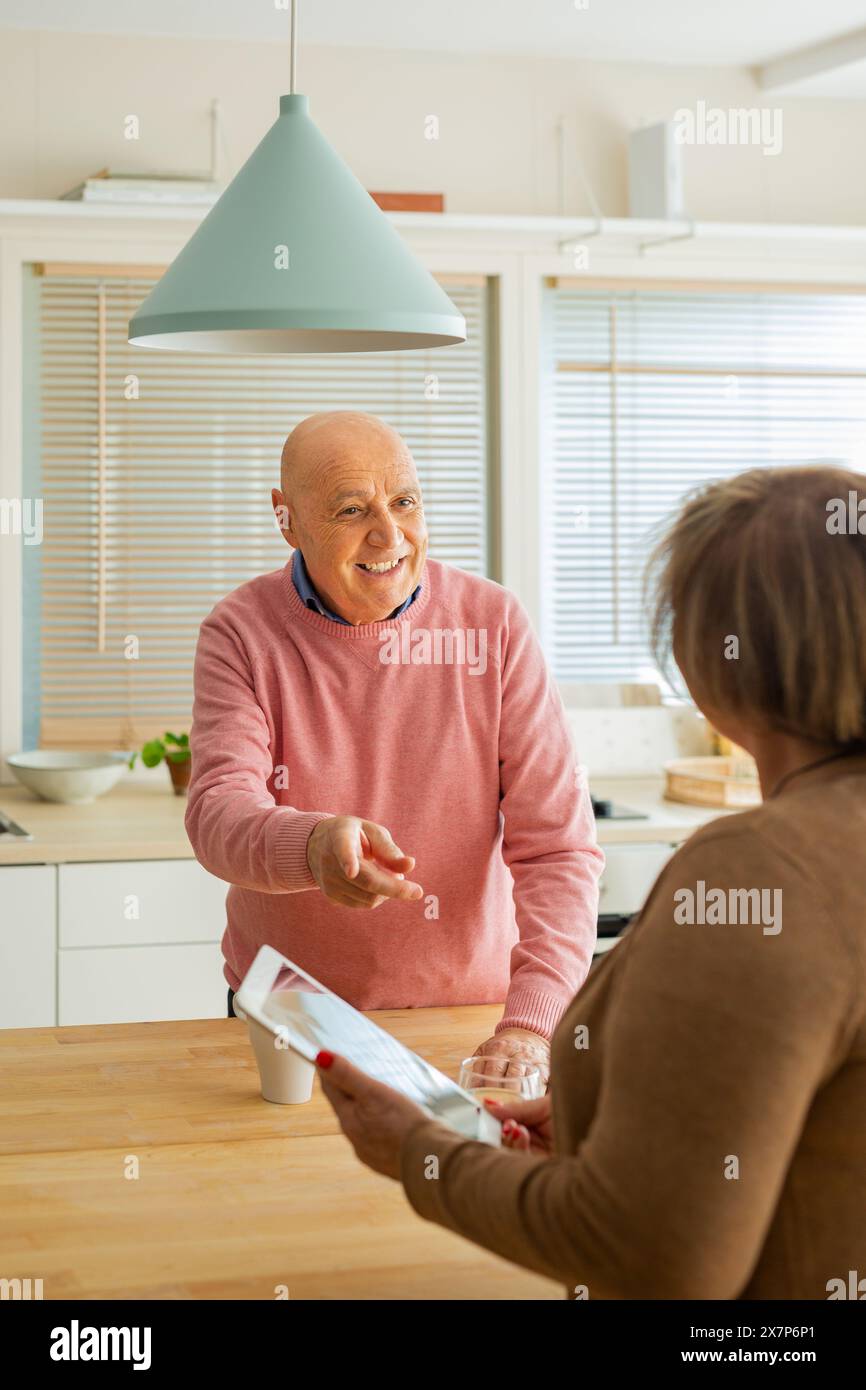 Elderly man smiling and pointing while having a conversation with his ...