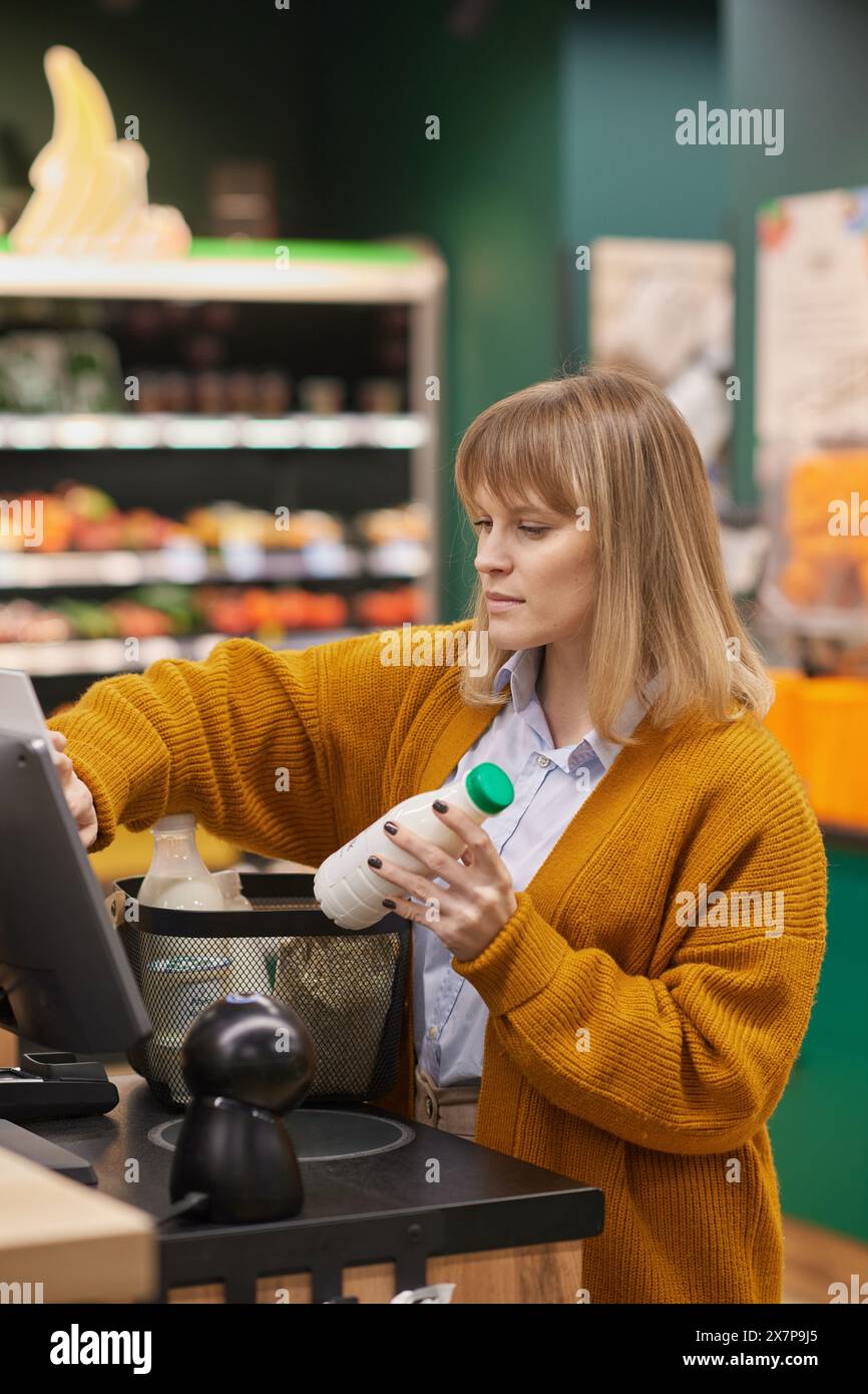 Vertical portrait of blonde adult woman using self checkout machine in ...