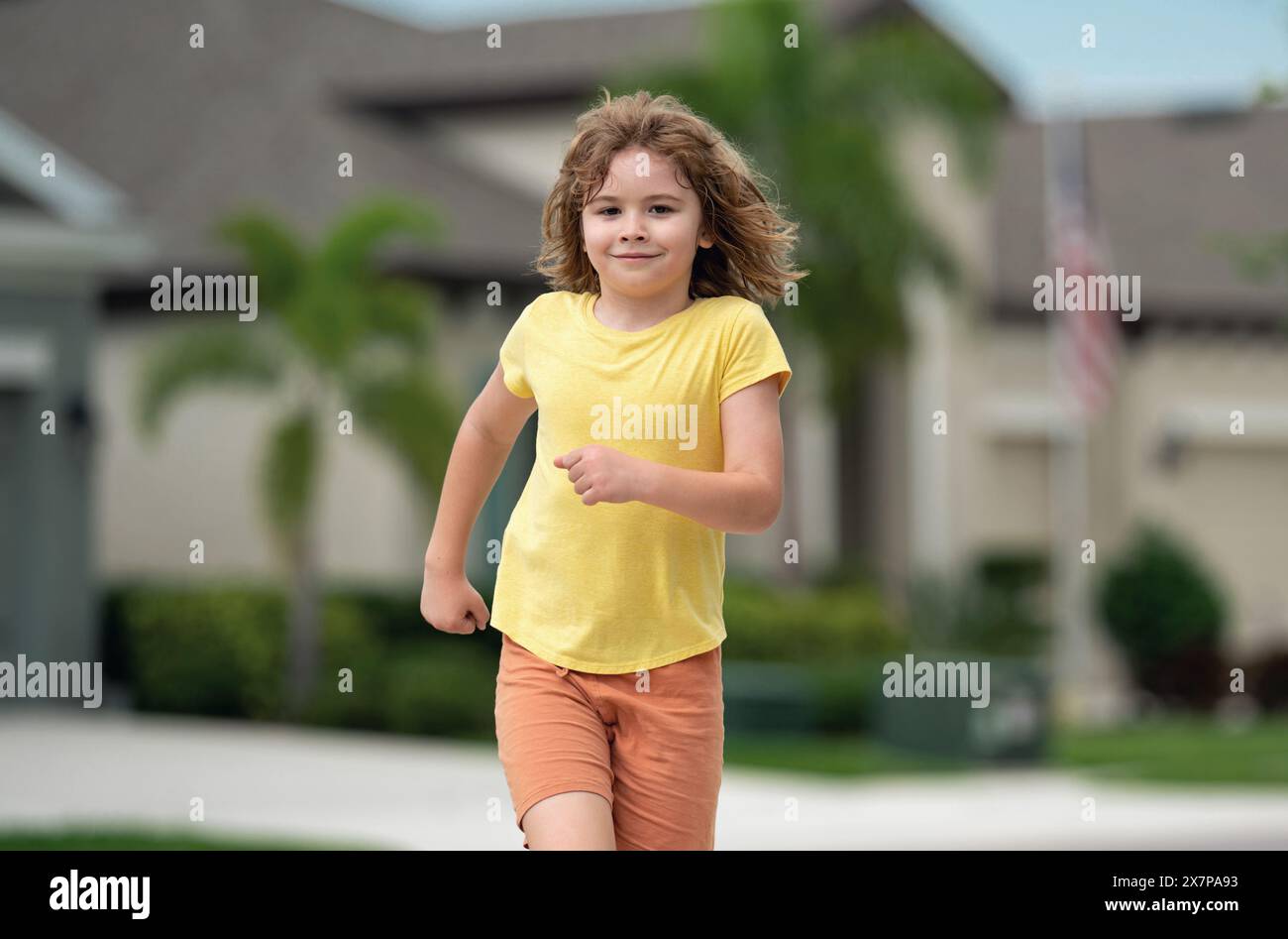 Cute kid boy running across american neighborhood street. Summer ...