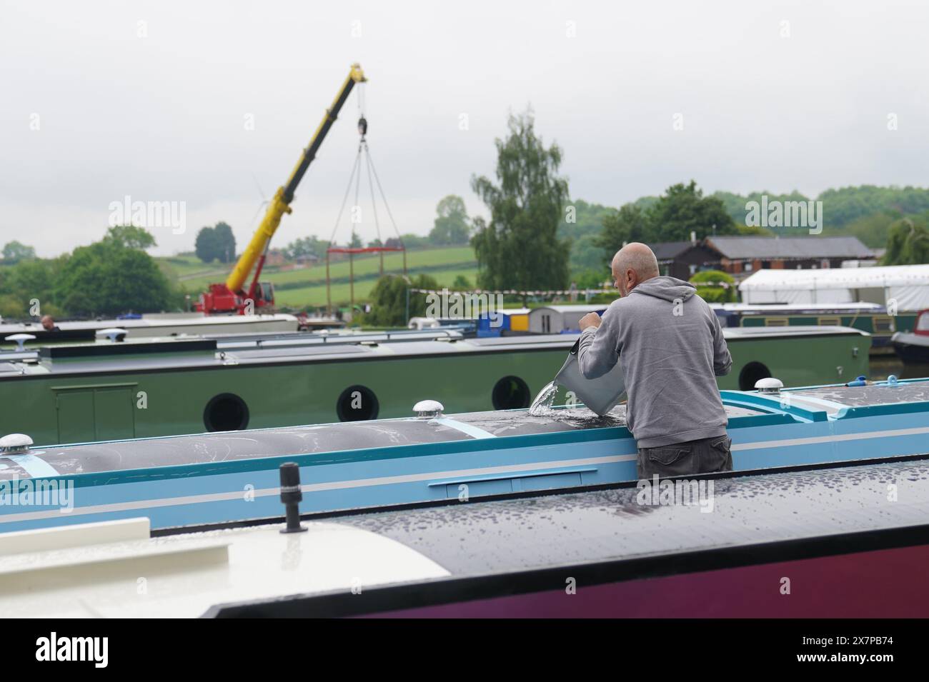 A man cleans a canal boat, at Crick Marina in Crick, Northamptonshire ...