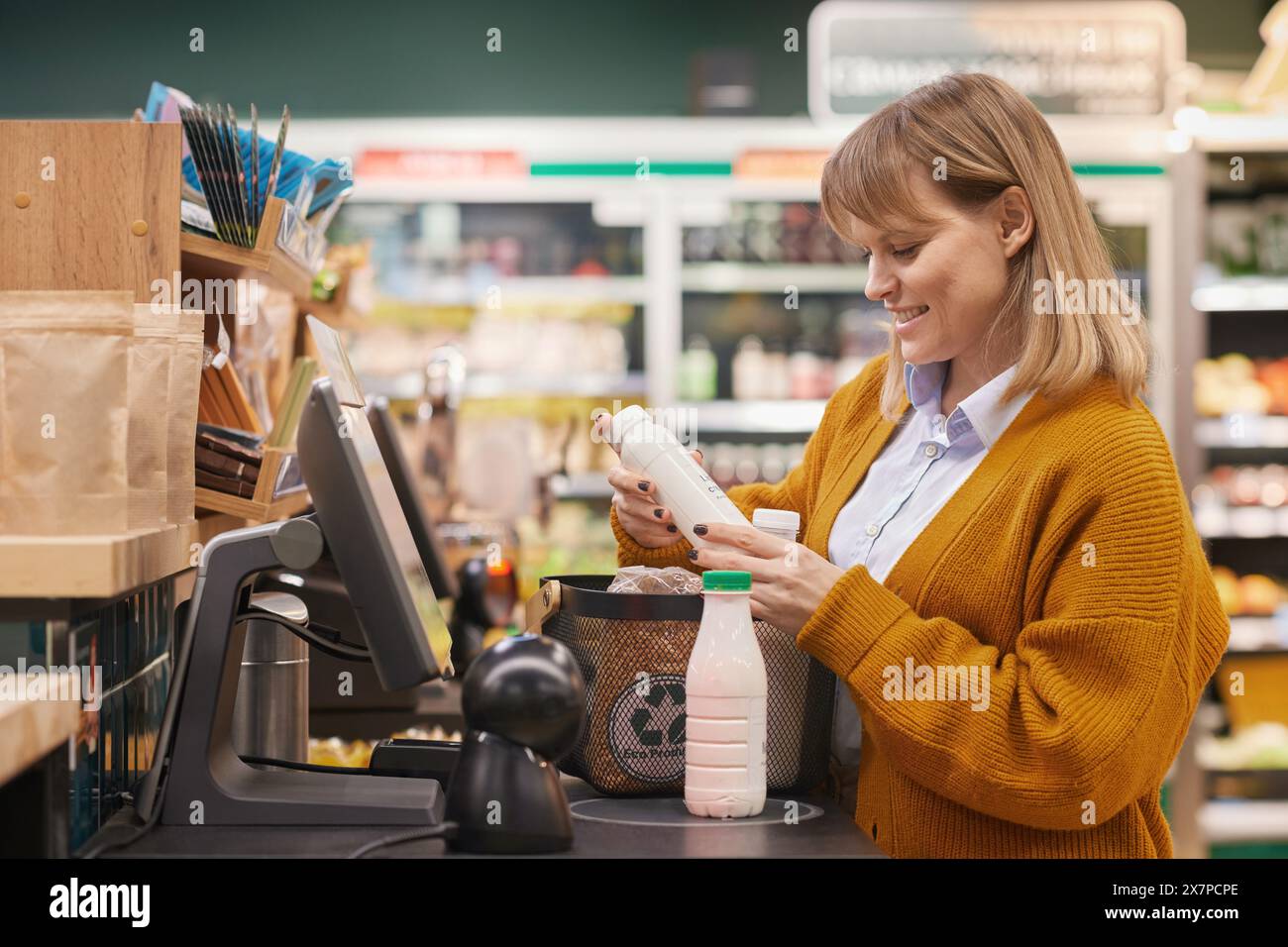Side view portrait of smiling Caucasian woman using self checkout ...
