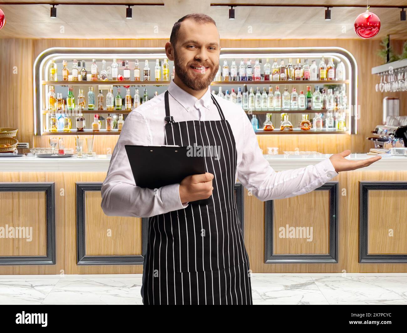 Waiter holding a menu and welcoming at a bar Stock Photo - Alamy