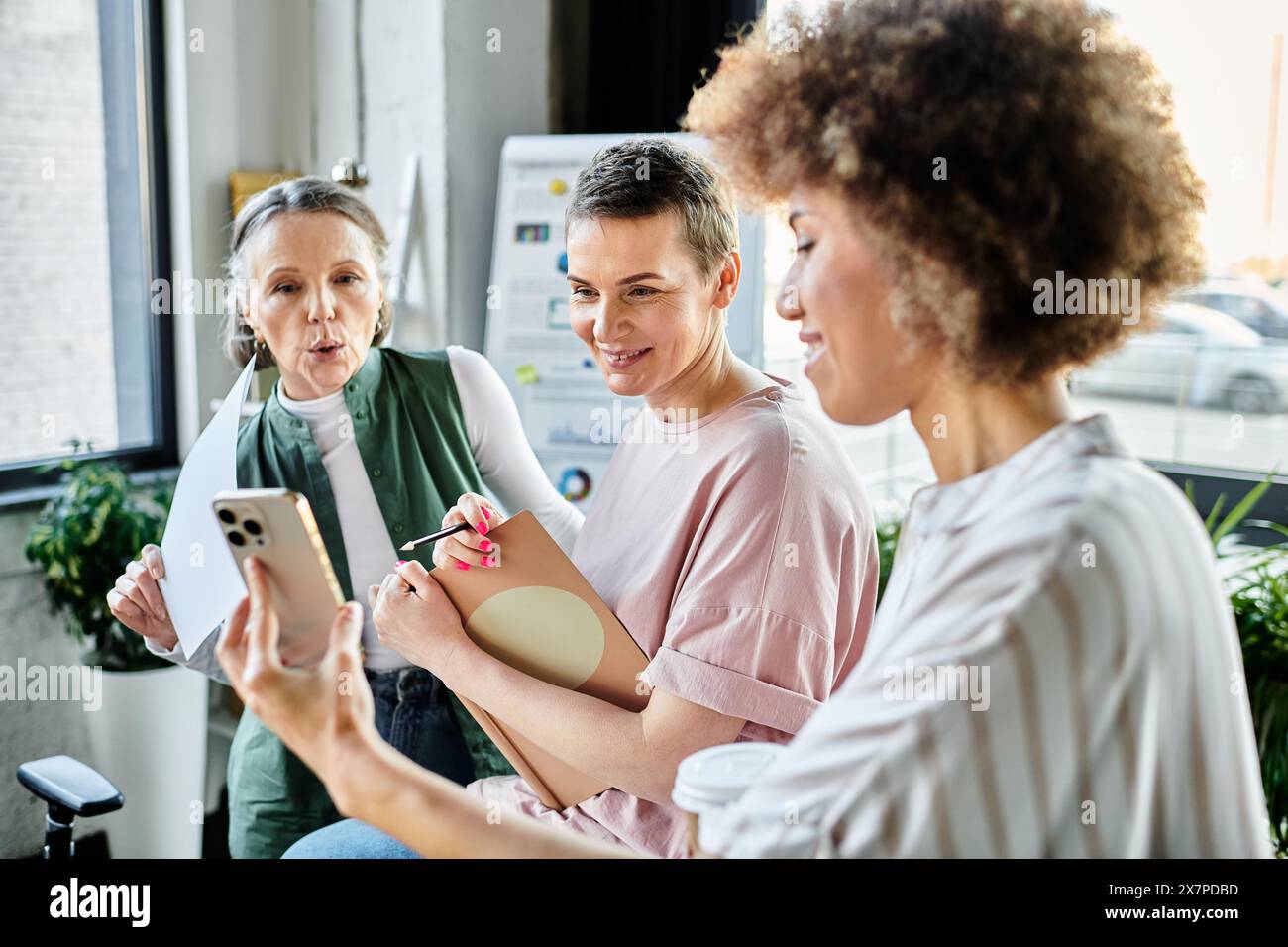 Diverse group of female professionals collaborating with a phone Stock ...