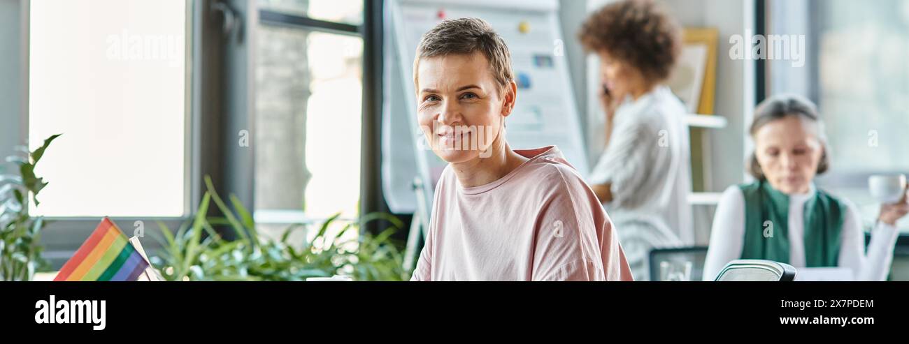 Jolly woman engrossed in work, with her diverse colleagues on backdrop ...