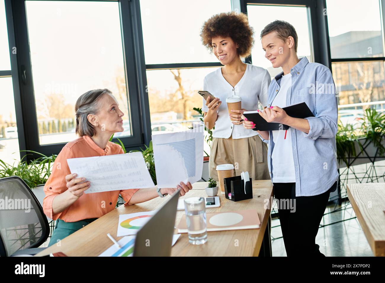 Diverse businesswomen collaborating around a table in an office setting ...
