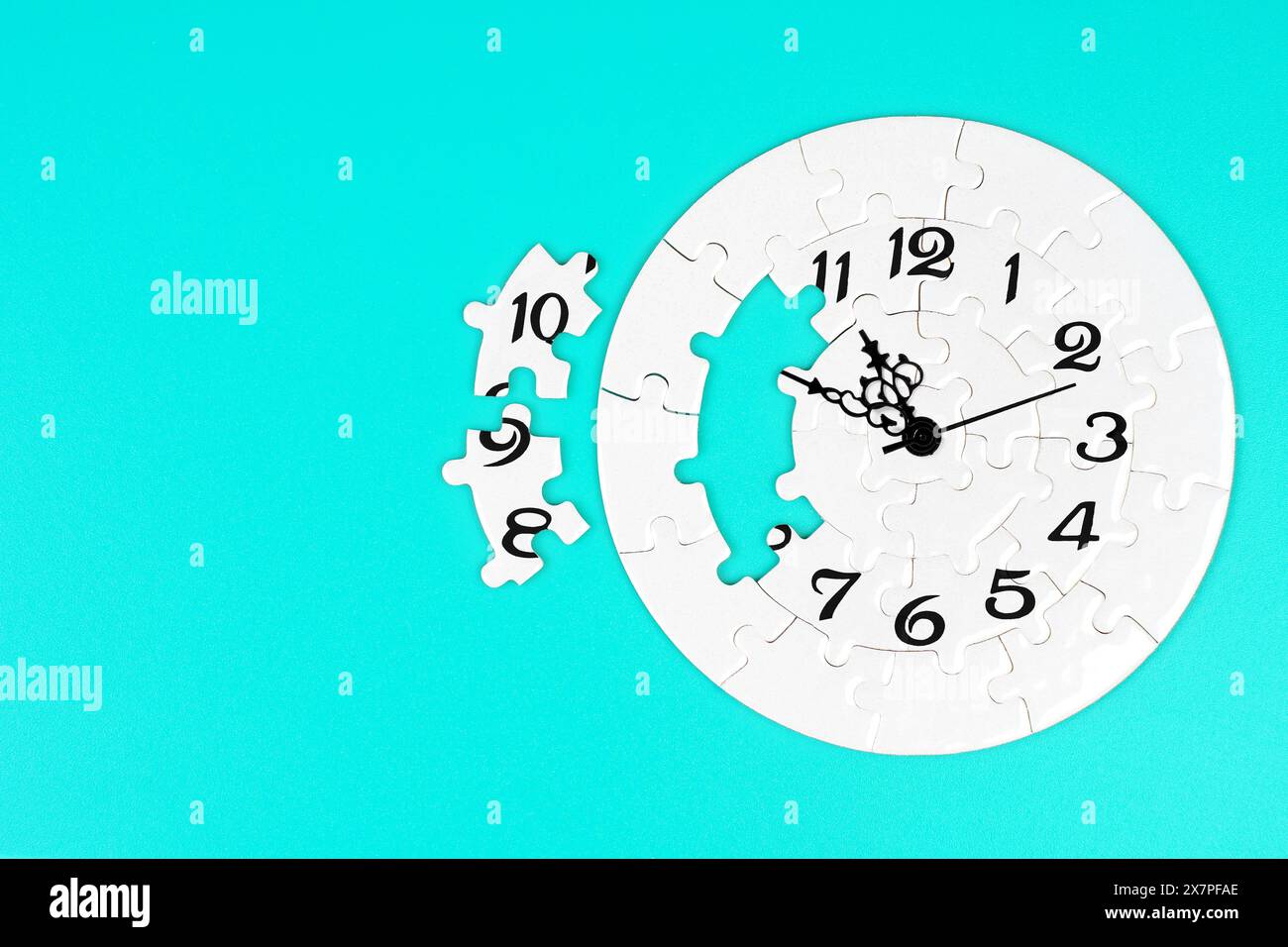 Incomplete clock face puzzle with two final pieces set aside on a blue ...