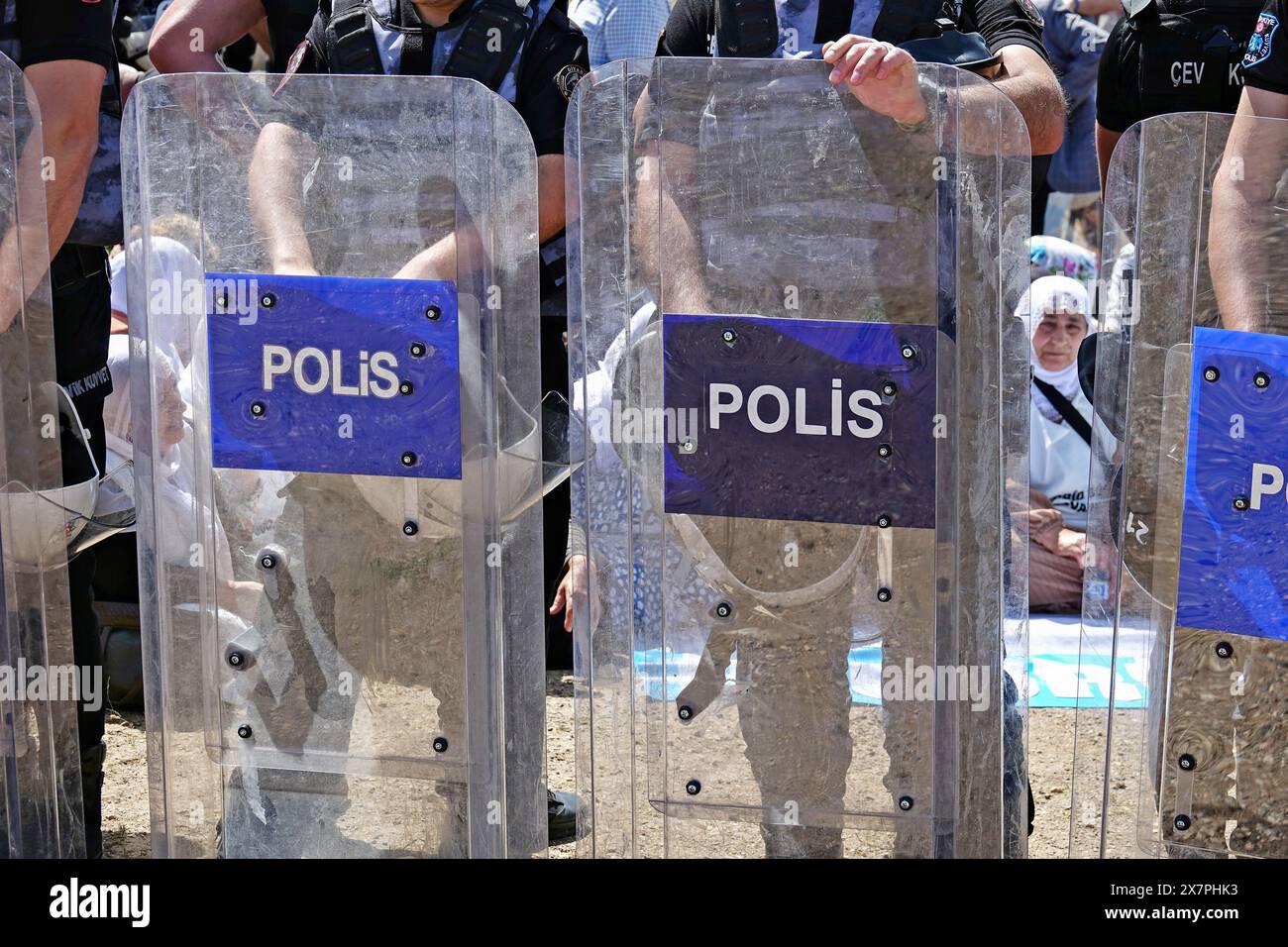 Police officers hold their shields to prevent media members from taking ...