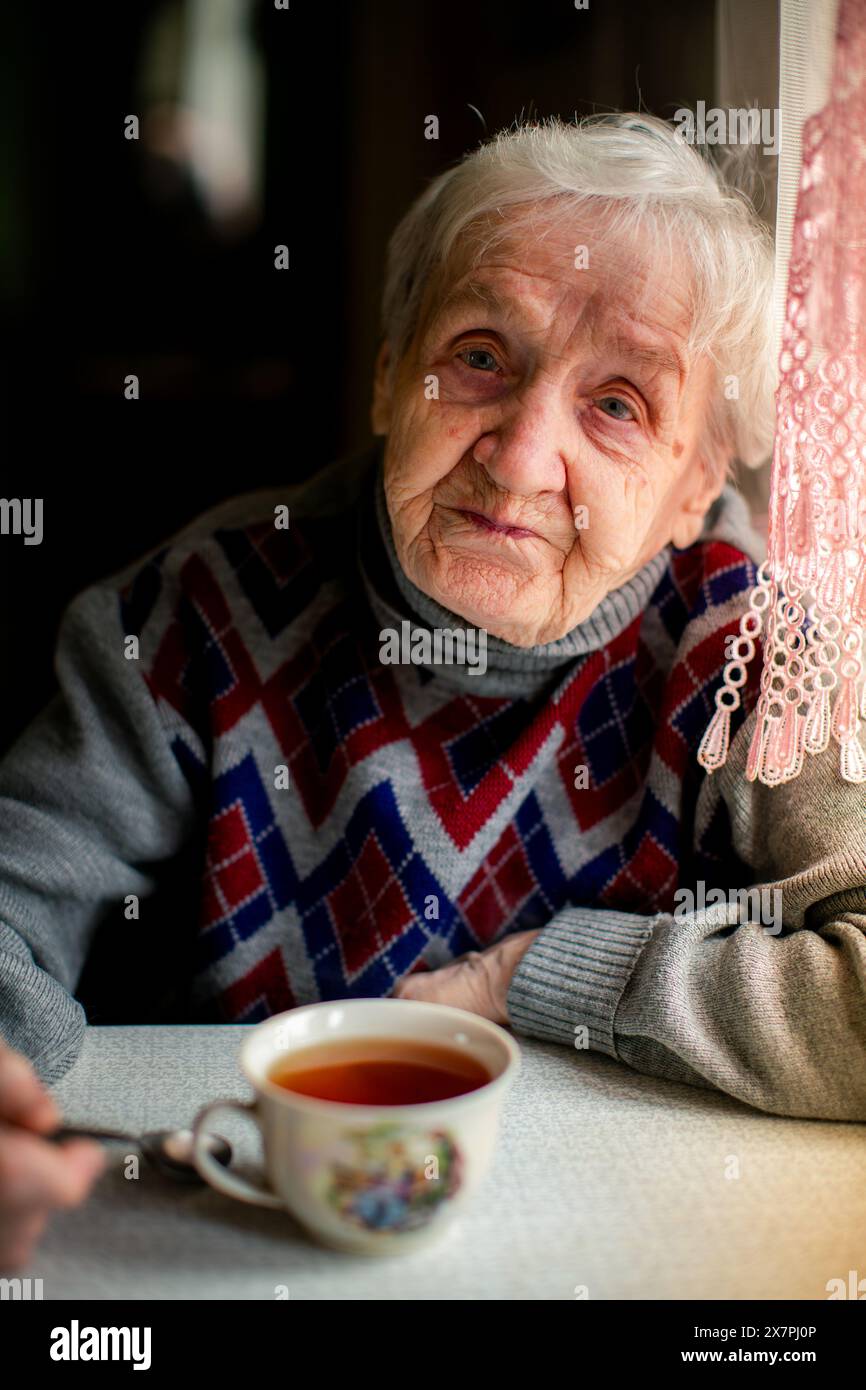 An elderly woman drinks tea by the window, portrait Stock Photo - Alamy