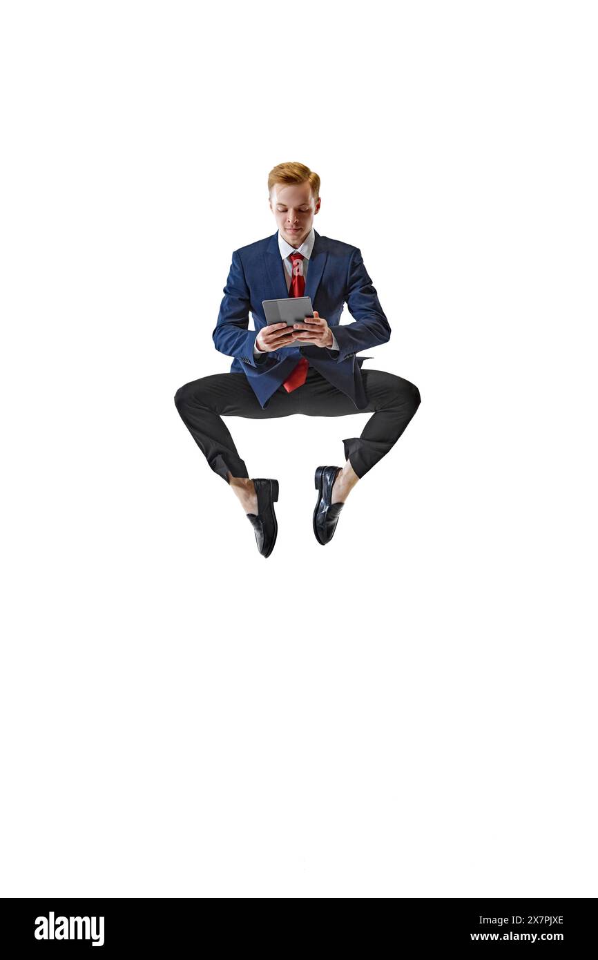 Focused on work or study young man in formal suit using tablet jumping ...