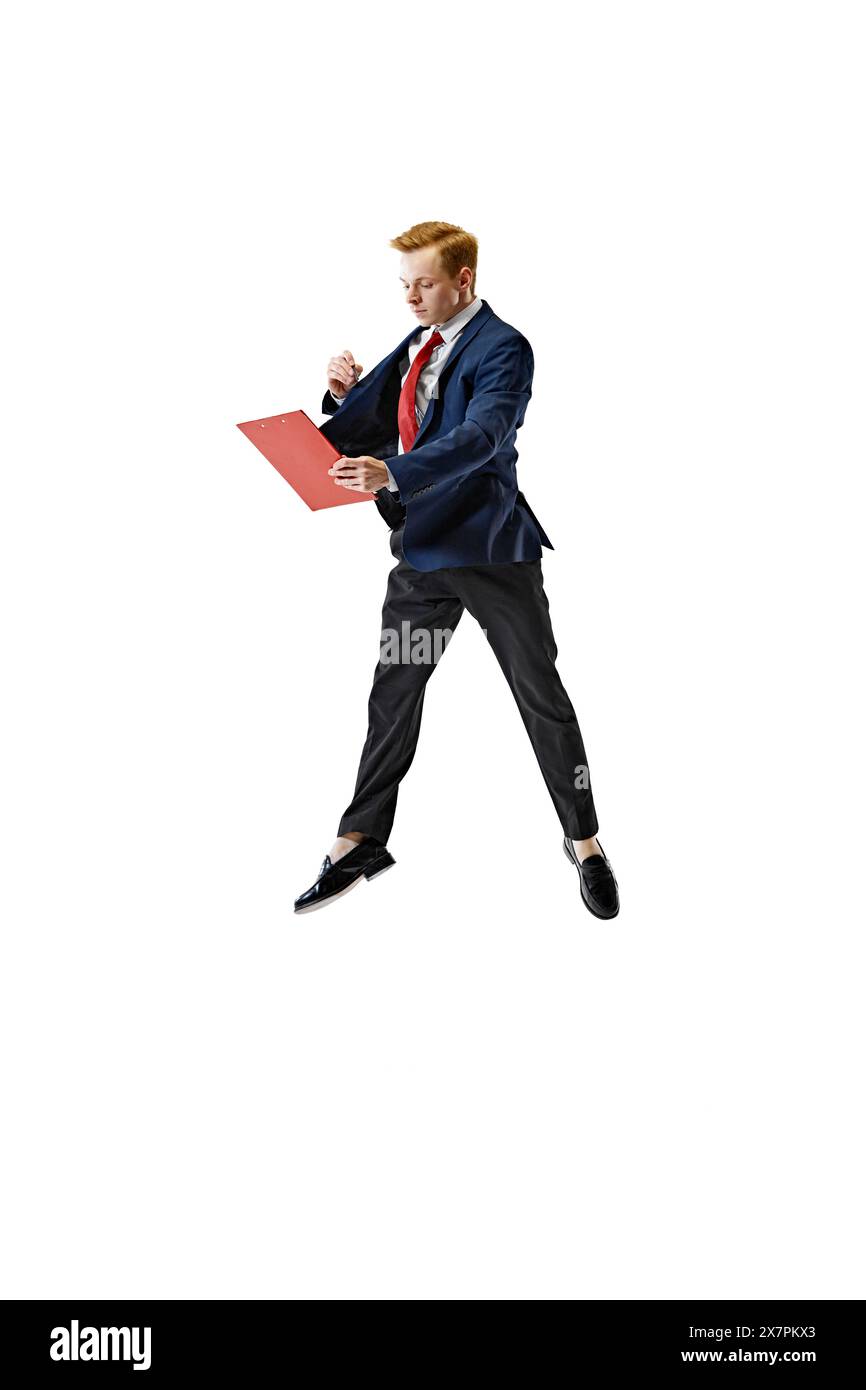 Young business man in formal attire in dynamic pose holding and reading ...