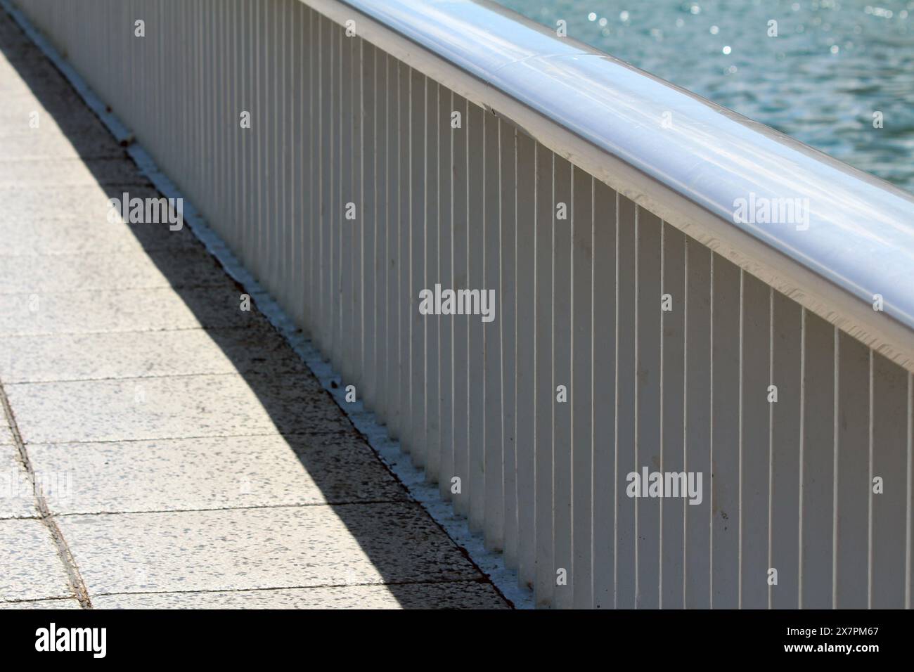 Dense row of grey vertical metal poles mounted on stone tiles ...